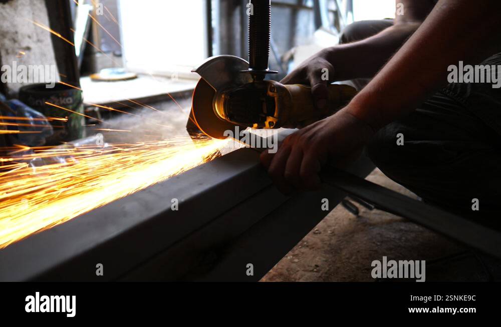 Male hands of young mechanic cuts iron using electric grind wheel at ...