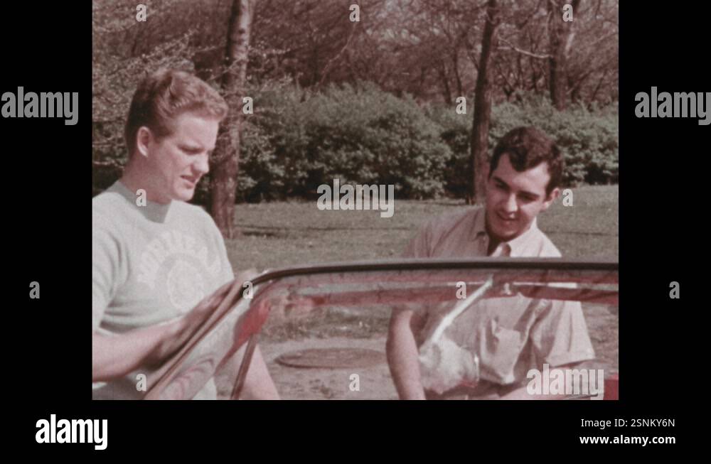 1960s: Two men talk while man wipes down car. Helix model of DNA, model ...