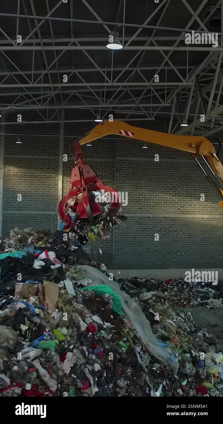 Industrial excavator sorting waste in a recycling facility, vertical ...