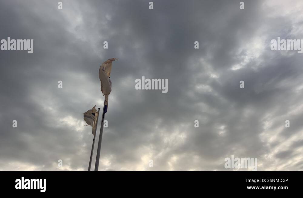 Two faded flags fluttering under a cloudy sky in barabate, andalusia ...
