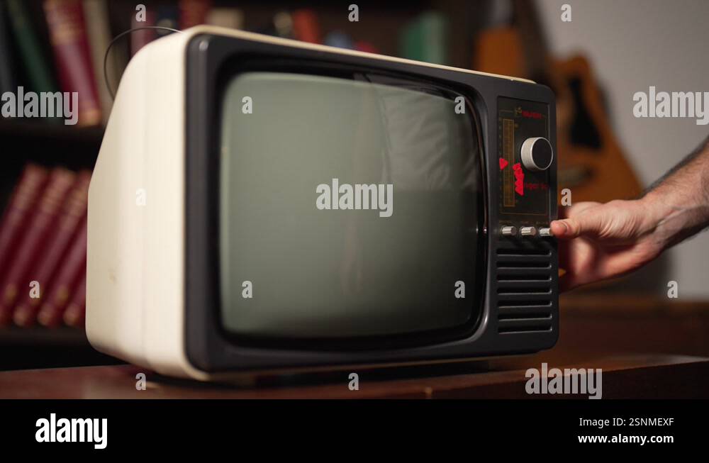 Man turns on vintage TV, pressing the button with his finger in slow ...