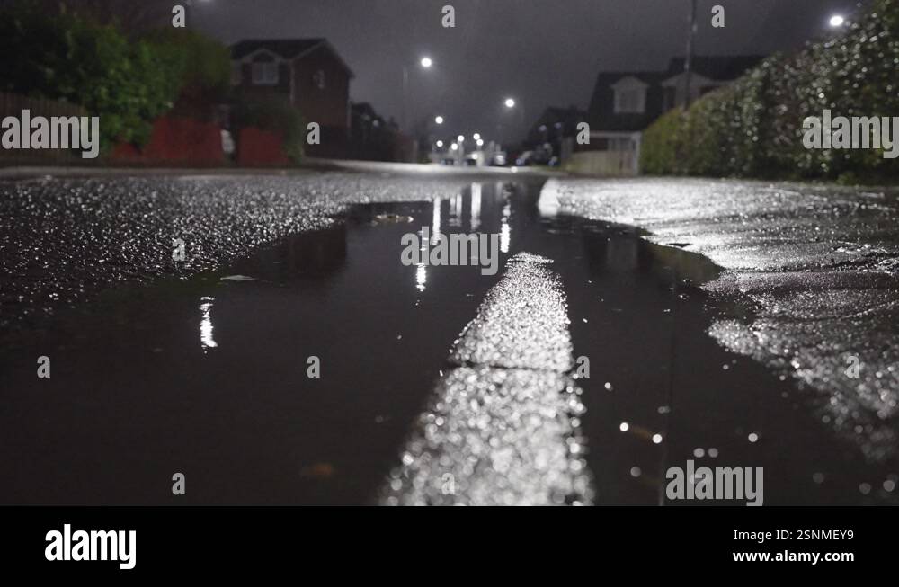 Drizzling rain, roadside puddles, street lights reflection, night scene Stock Video Footage - Alamy