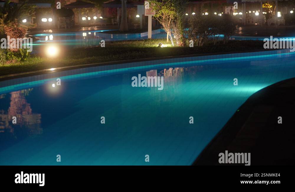 Pool with warm evening lighting. Swimming pool at night with neon light ...
