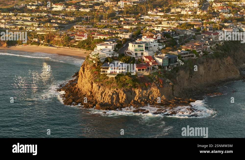 Drone view of a rugged cape with luxurious vacation homes at golden ...