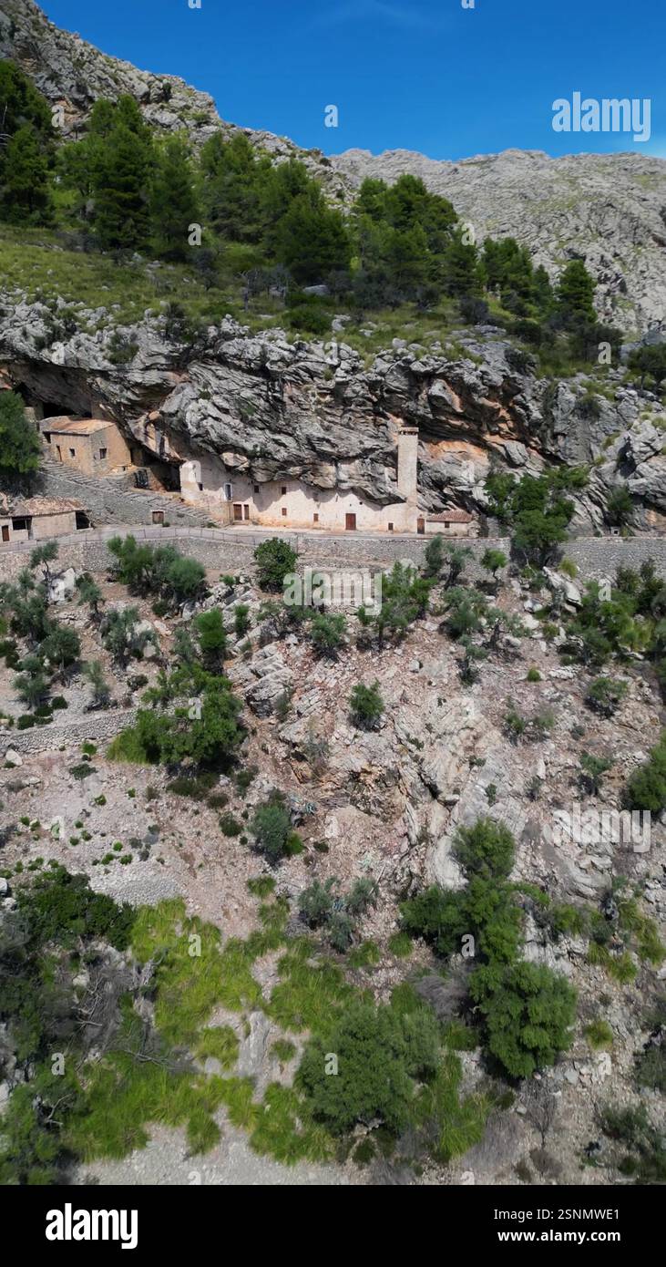 Traditional stone buildings are nestled into a cliffside on the ...