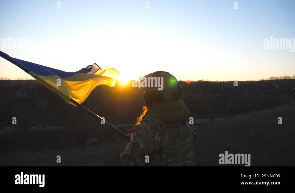 Woman in military uniform waving blue-yellow flag against background of ...