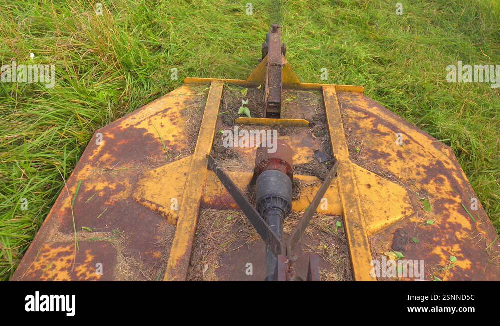 Brush hog cutting grass attached to a farm tractor using three-point ...