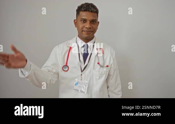 Doctor wearing white coat and stethoscope waves with a smile on his ...