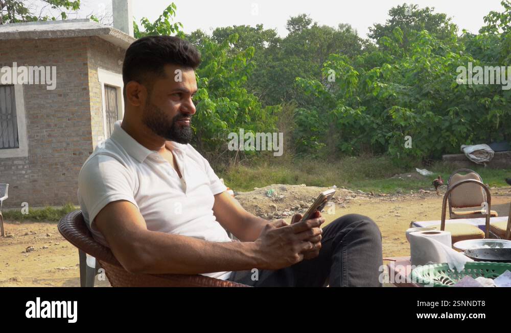 An Asian man lounges at a sidewalk café, nonchalantly tapping away on ...