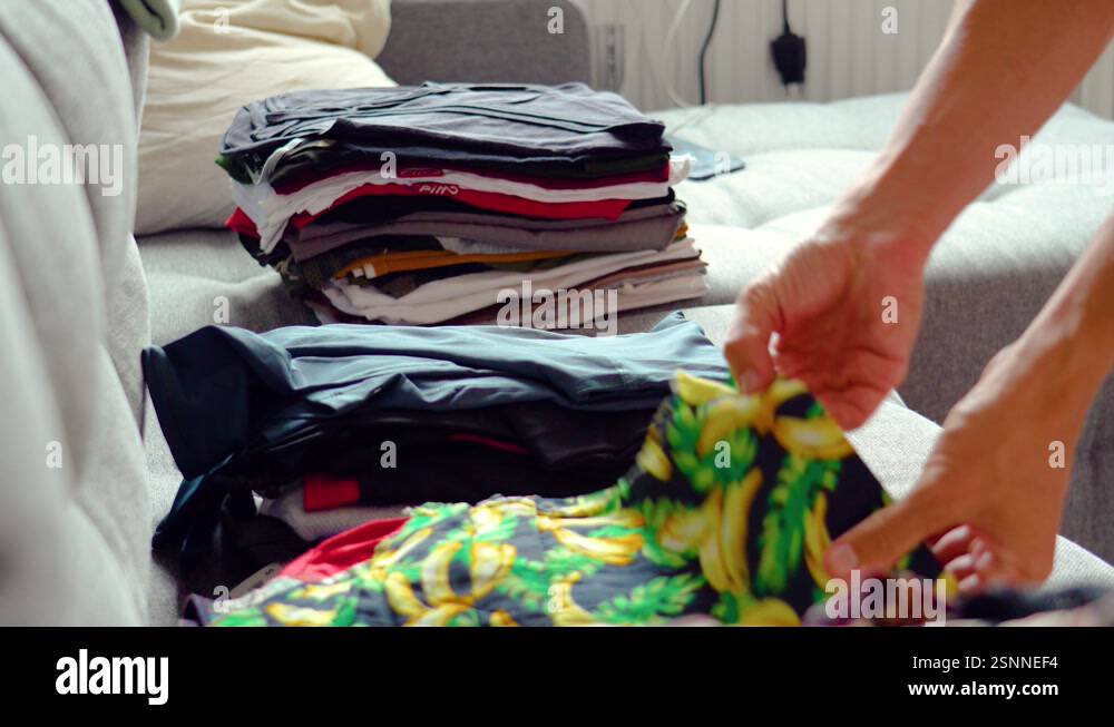 fold clothes wardrobe on the sofa, sort through the collection of things stack Stock Video ...