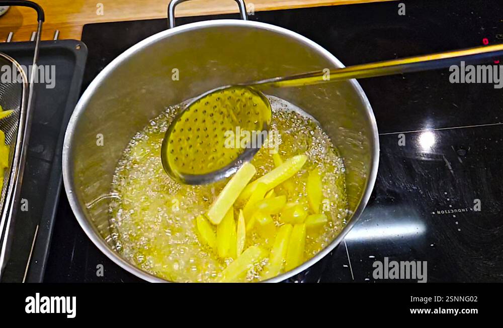 First person view of a hand mixing and spinning golden yellow fries or ...