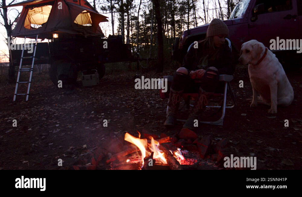 Gen Z female sitting by campfire on a wilderness Jeep adventure with ...
