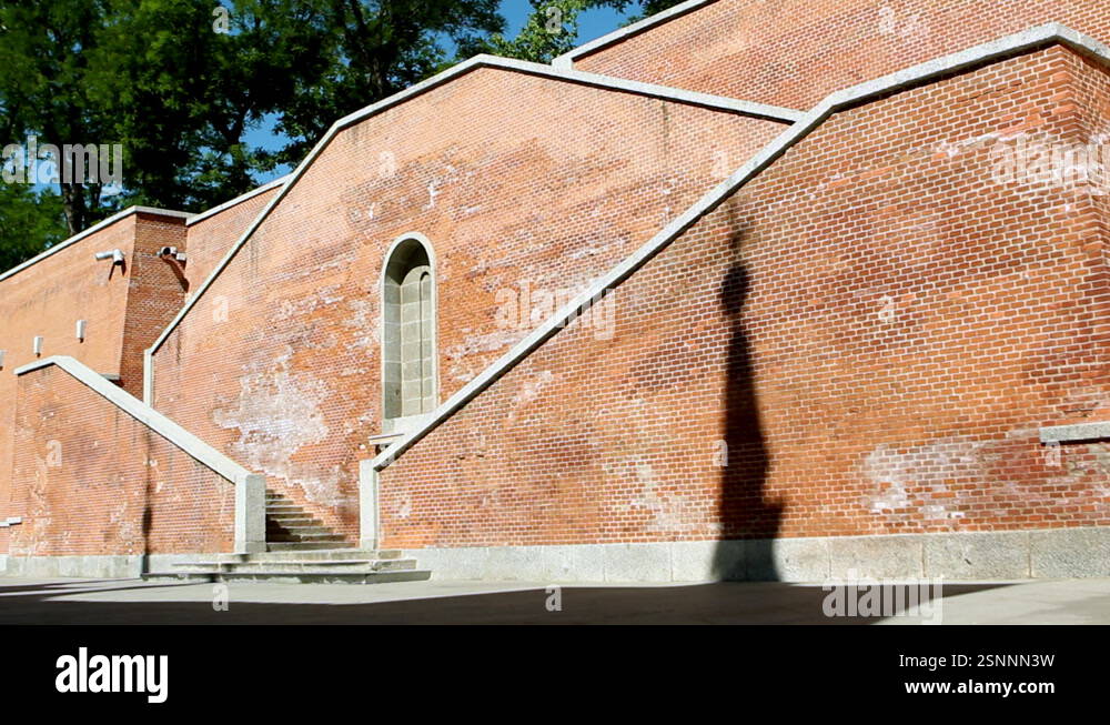 Sunlit red brick building with geometric stairs and an arched window ...