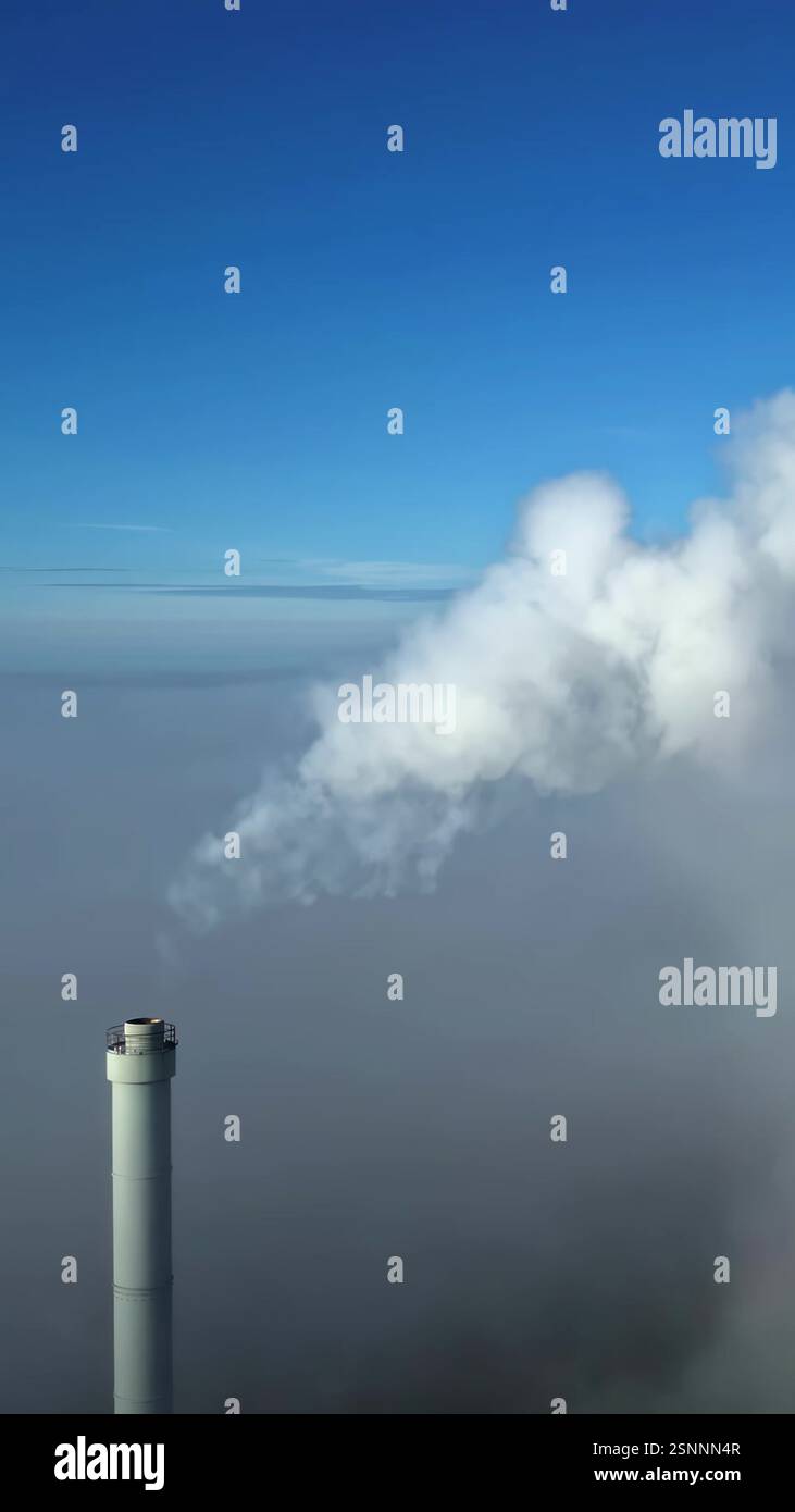 Vertical shot of a factory chimney, waste air spreads in the sky, air ...