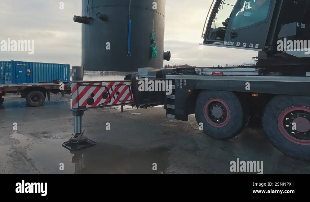 Crane pulls a large tank from a truck trailer. A tank made of ...