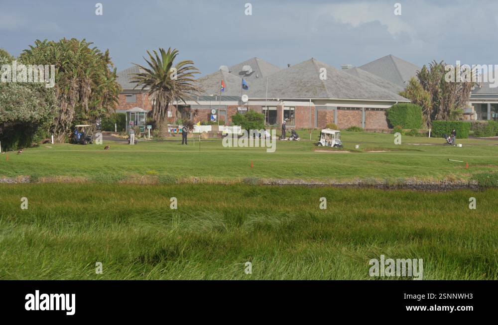 Golf course with clubhouse on a windy day surrounded by lush greenery ...