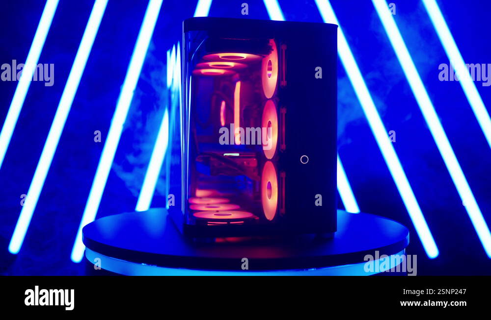 Zoom in on RGB gaming computer on turning platform with neon tubes ...
