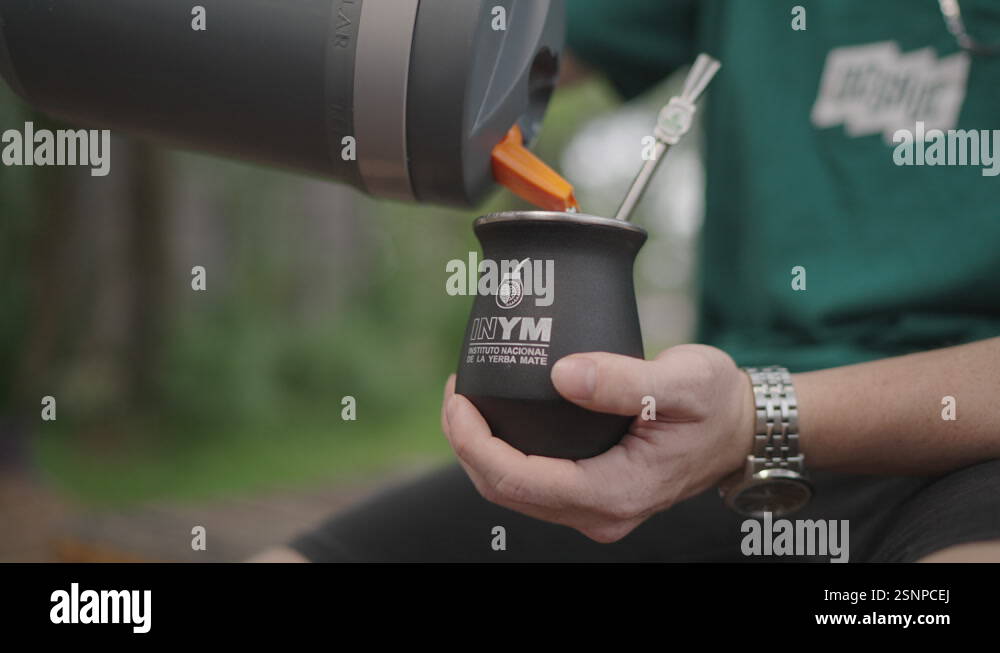 Man pouring cold water from thermos into to prepare tereré traditional ...