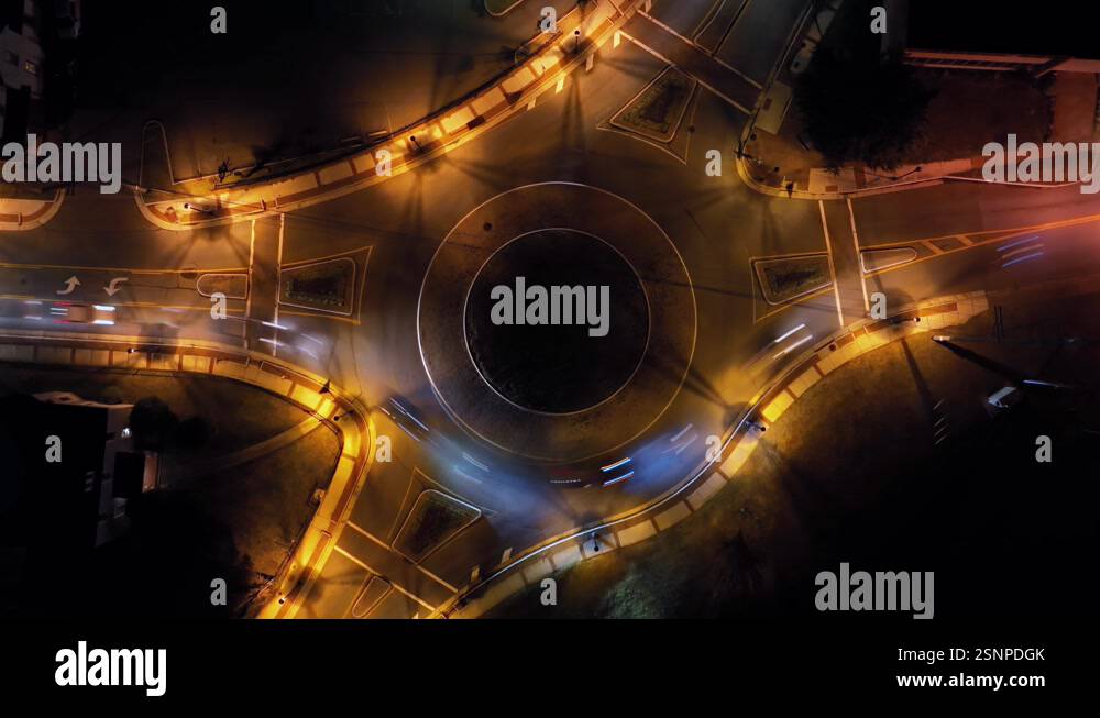 Busy traffic on roundabout in american town at night. Time lapse drone ...