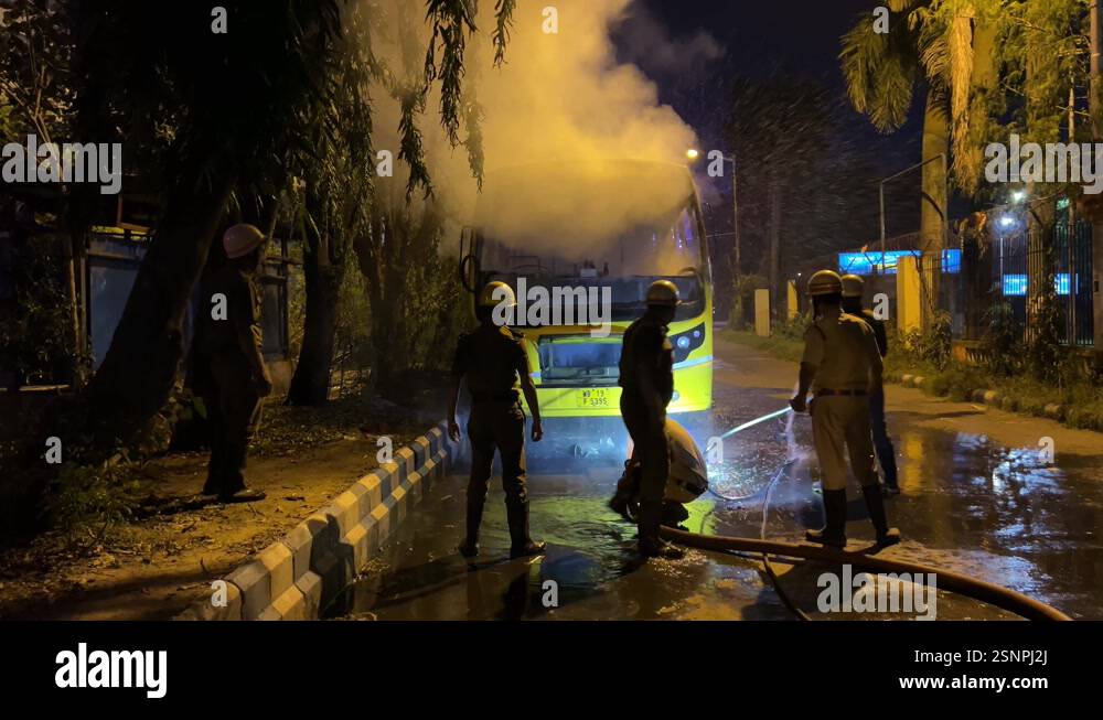 A static shot of a burning bus in India with smoke billowing from the ...