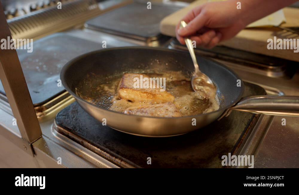 Chef Stirring and Basting Fish Fillet with Butter in Pan Over Stove ...