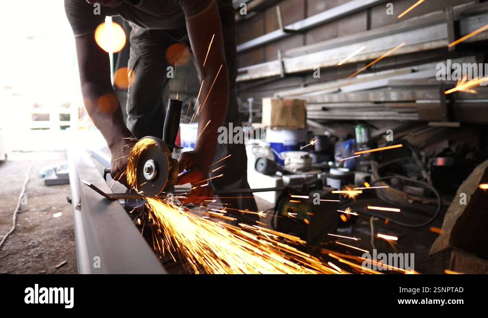 Male hands of young craftsman cuts iron using electric grind wheel at ...