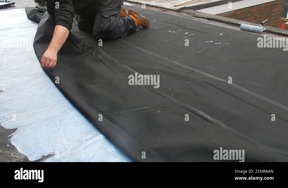 Man covering flat roof rolling rubber waterproof sheet to prevent ...
