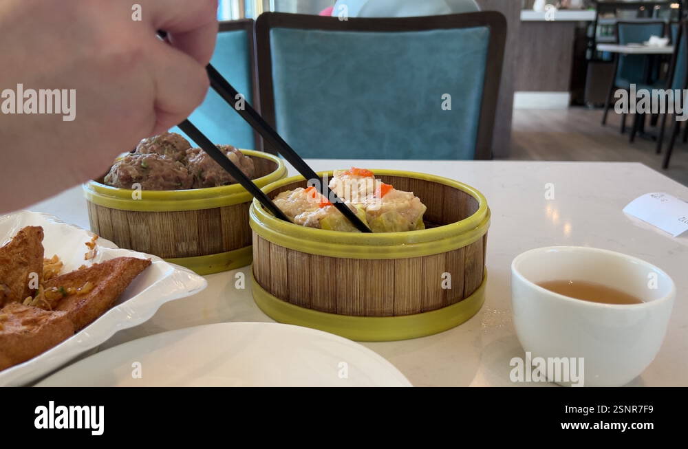 Enjoying Dim Sum: Man Picking Up Siomai with Chopsticks at Restaurant ...