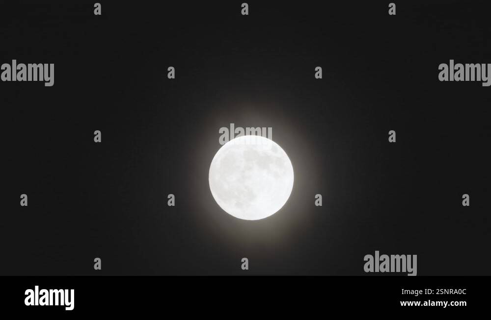 Wispy clouds drift across the face of the full moon rising Stock Video Footage - Alamy