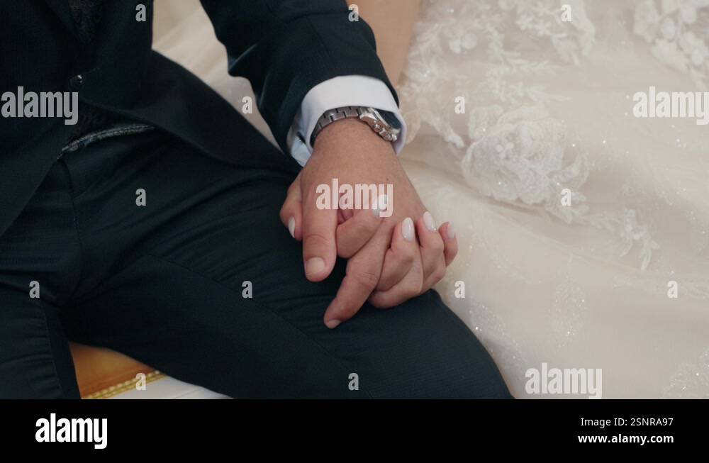 Bride and groom holding hands in wedding attire during ceremony moment ...