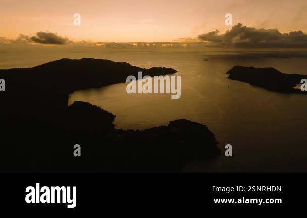 Island silhouettes fading into calm waters under a softly illuminated ...