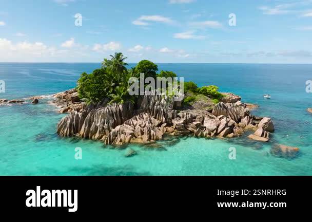 Granite boulders, tropical trees, and crystal-clear waters form a ...