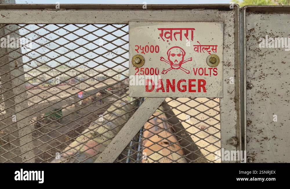 Danger Sign of 25,000 Volts over a rail over bridge it is placed at the ...