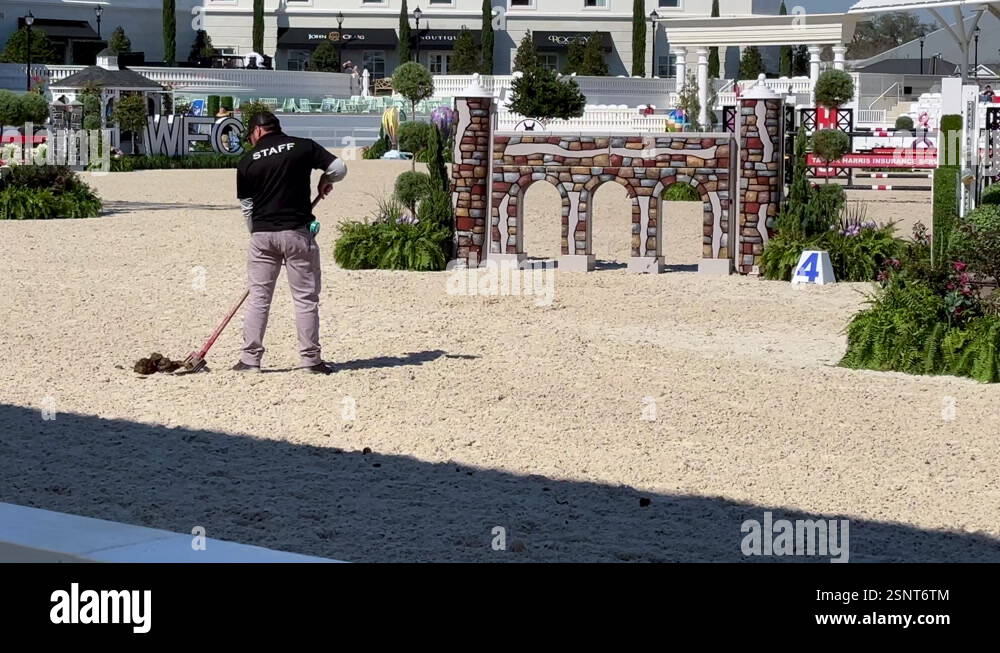 Male crew hand shoveling horse manure at equestrian dressage ...