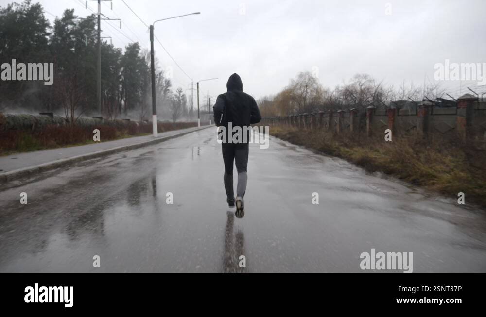 Strong athlete in sportswear jogging along trail at cloudy day ...