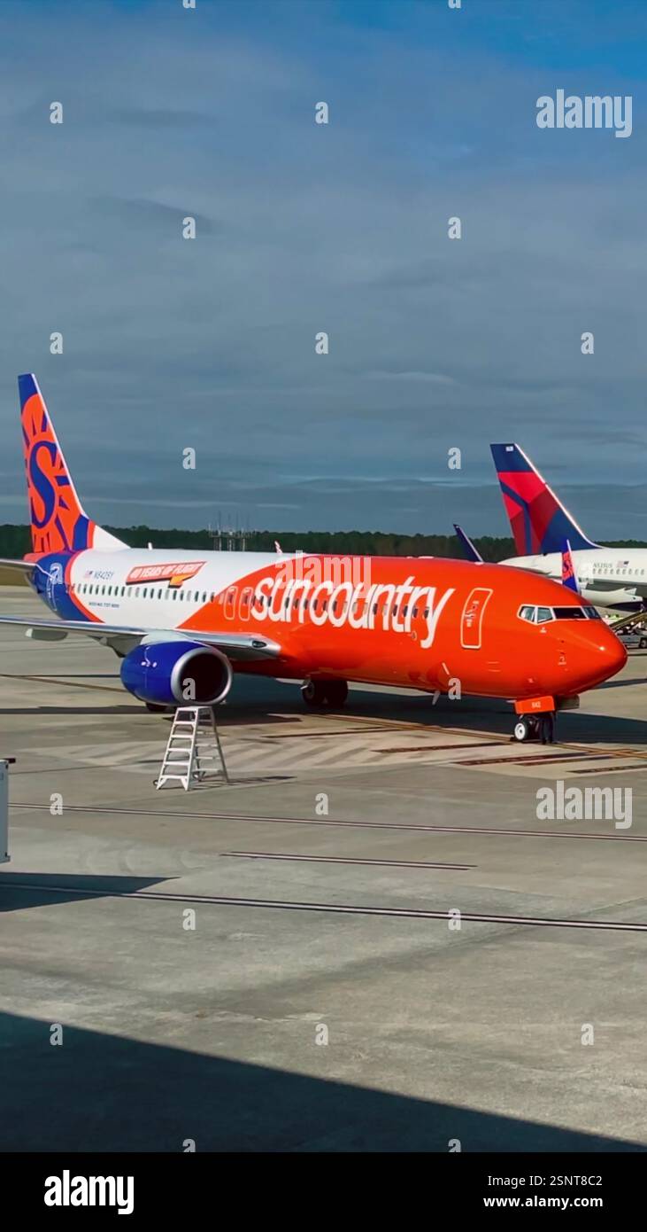 Passenger jet parked on tarmac at busy airport with maintenance crew ...