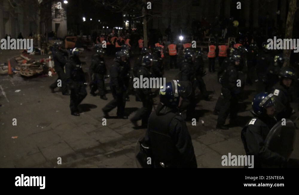 Metropolitan Police In Riot Helmets And Shields Walk Past A Barricade ...