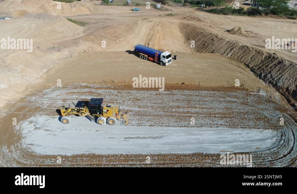 Grader mixes lime into soil to dry ground for construction foundation ...