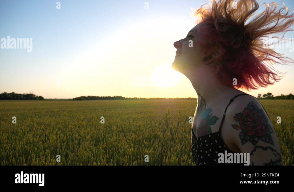 Carefree hippie woman rising head and waving her hair in air at barley ...