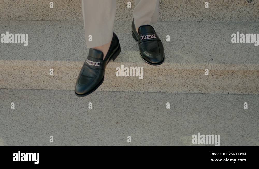 Man walking downstairs outdoors in slow motion wearing sleek leather ...