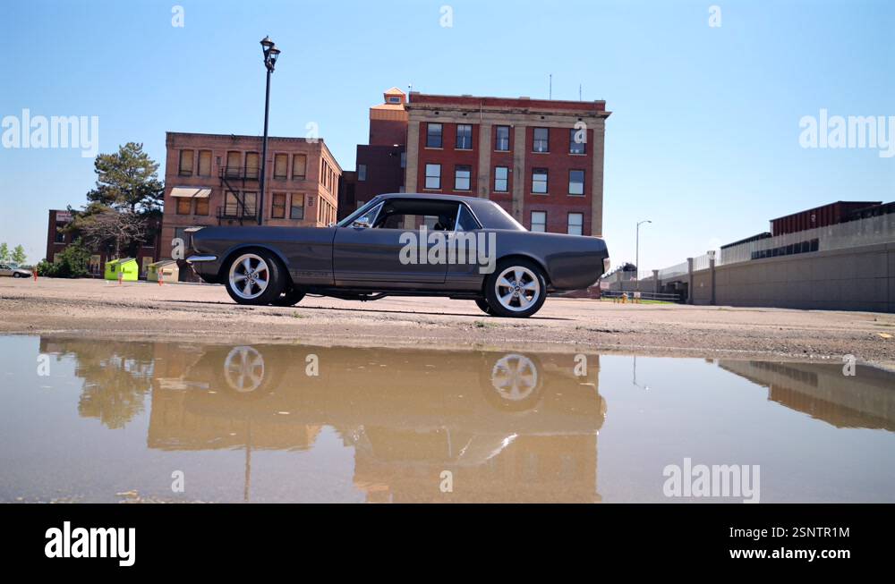 Restored 1965 Ford Mustang Reflected in Puddle in Industrial Setting ...