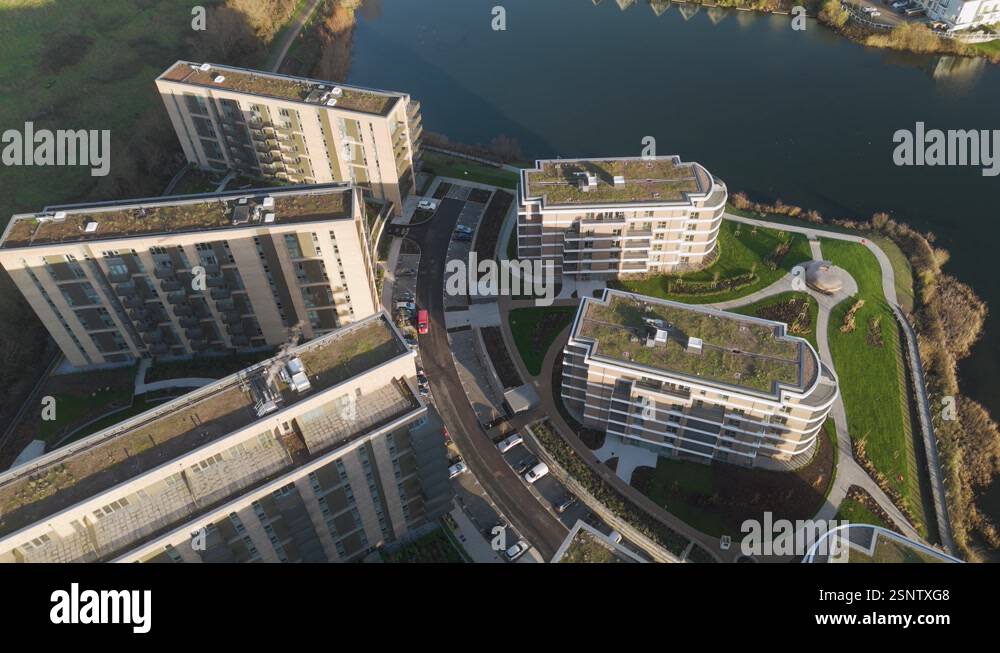Orbital aerial of a luxury housing development by a lake at golden hour ...