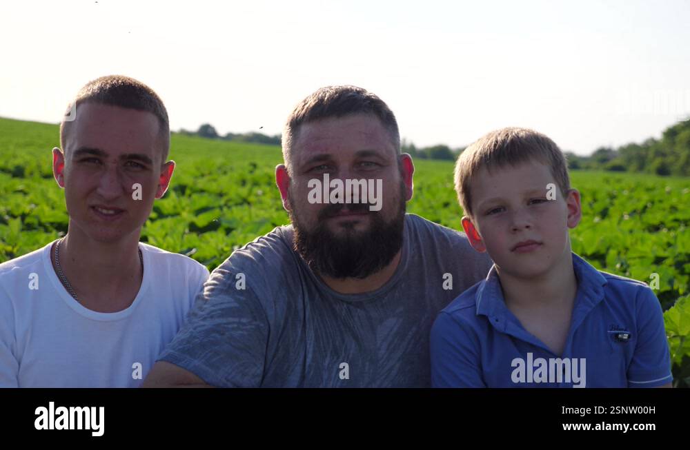 Portrait of daddy and children at cultivated meadow. Father with two ...