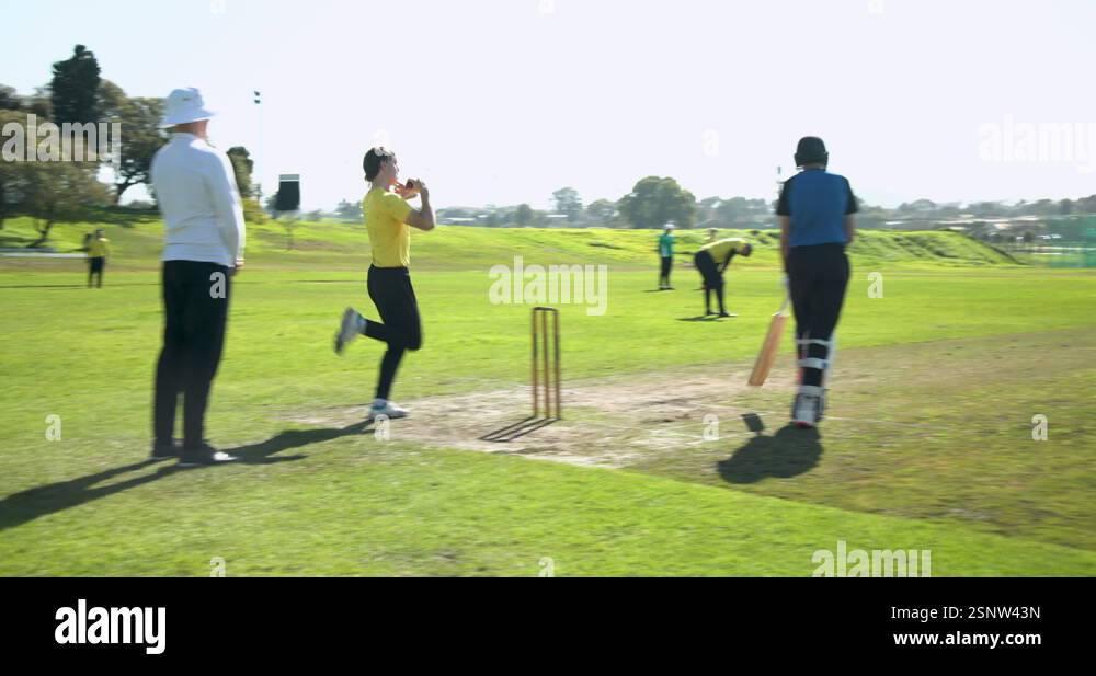 Cricket players running between wickets on sunny field, focusing on ...
