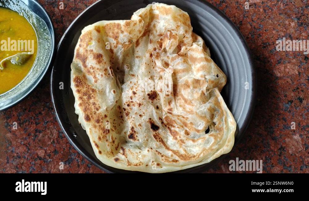 A serving of roti canai, a popular Malaysian dish, placed on a table ...