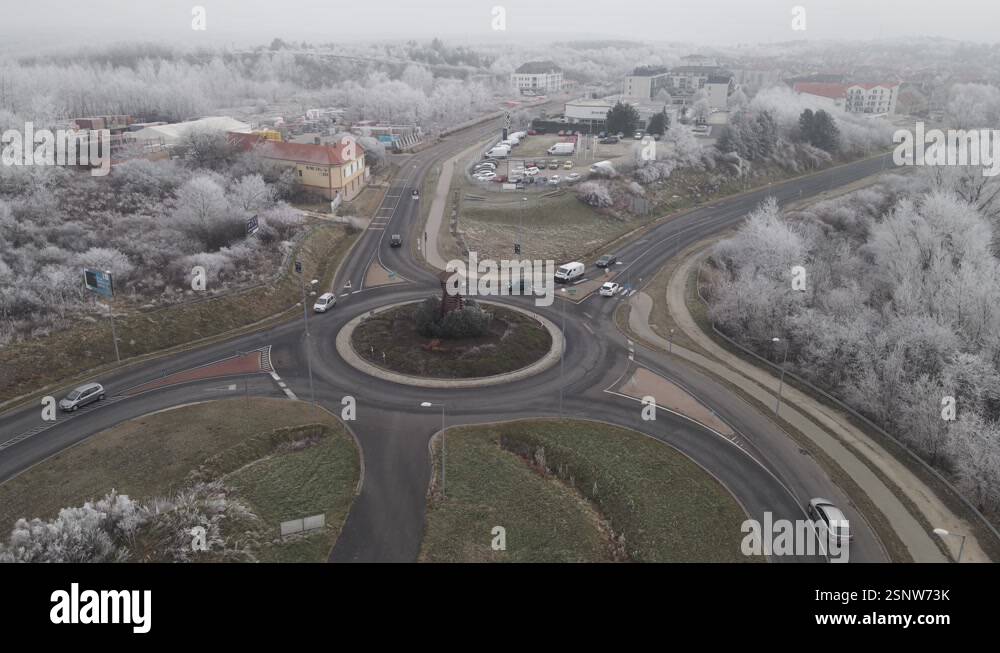 An aerial footage of a roundabout surrounded by frost-covered trees and ...