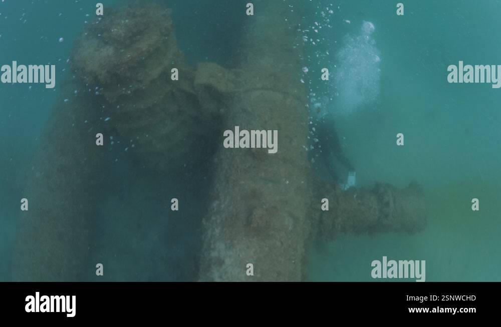 Scuba divers working on an underwater pipe structure deep below the ...