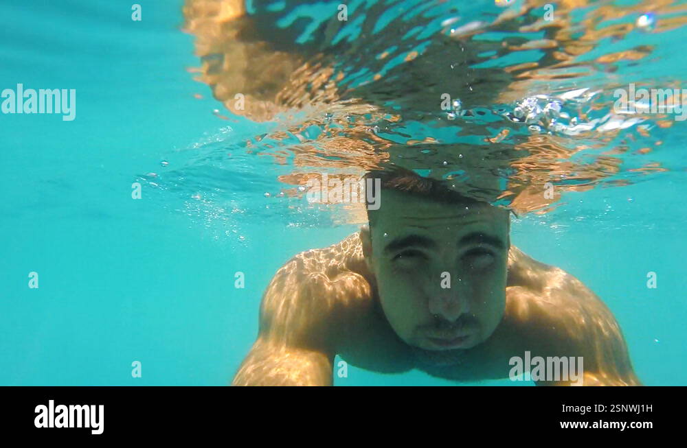 Portrait of young man diving in sea. Guy swims under water and filming ...