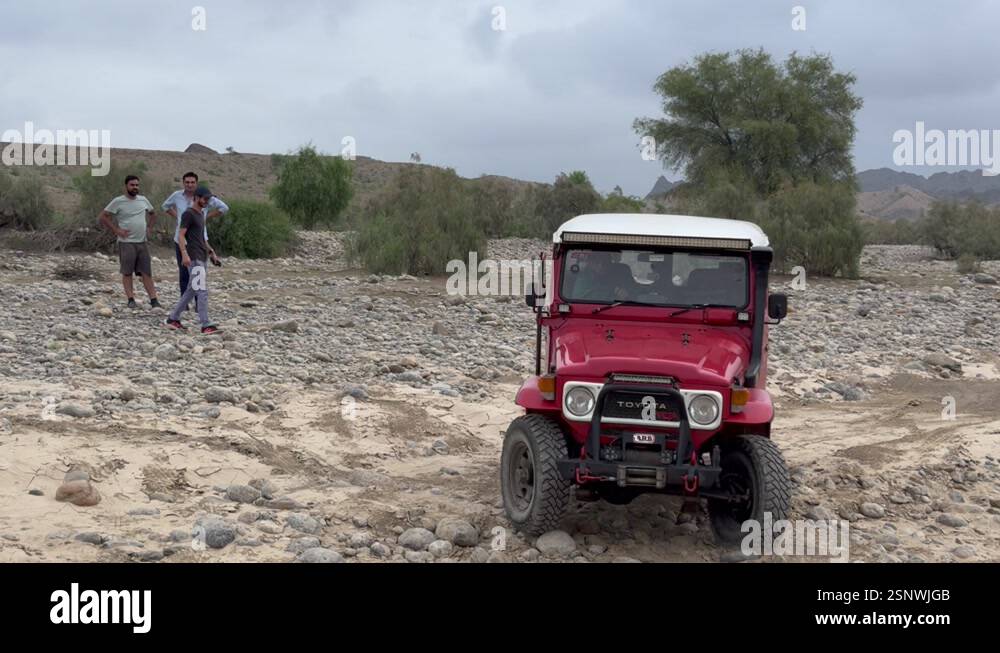 Red jeep driving off road under cloudy day in Balochistan, Pakistan ...