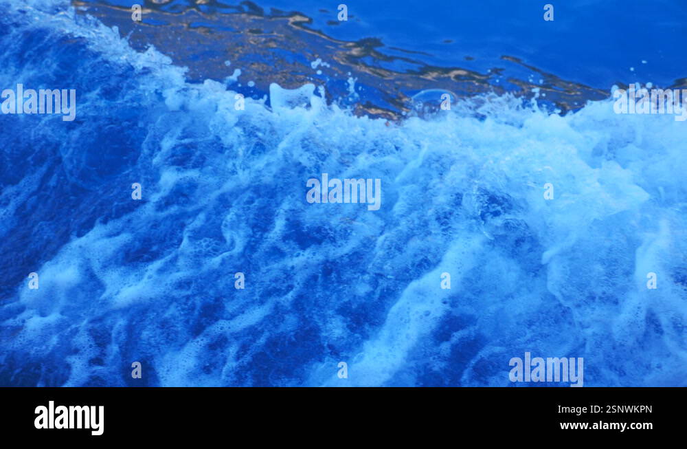 View from side of motor boat swimming and splashing clear sea water ...